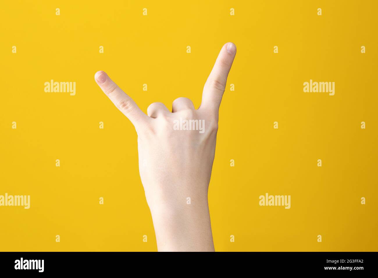 hand of teenager with two raised fingers in shape of goat with yellow ...