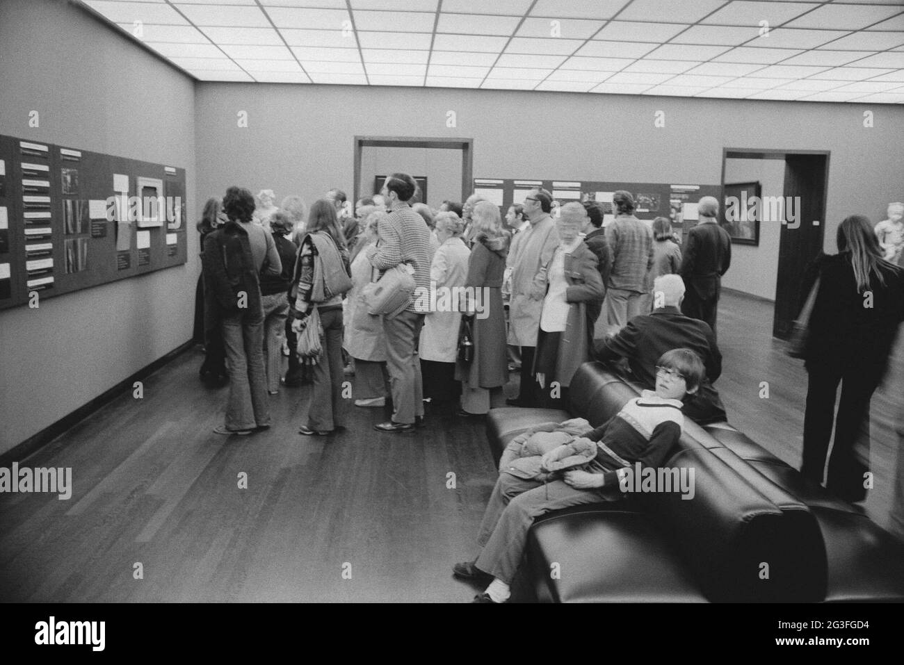 Room with information panels on the wall and visitors including a boy ...