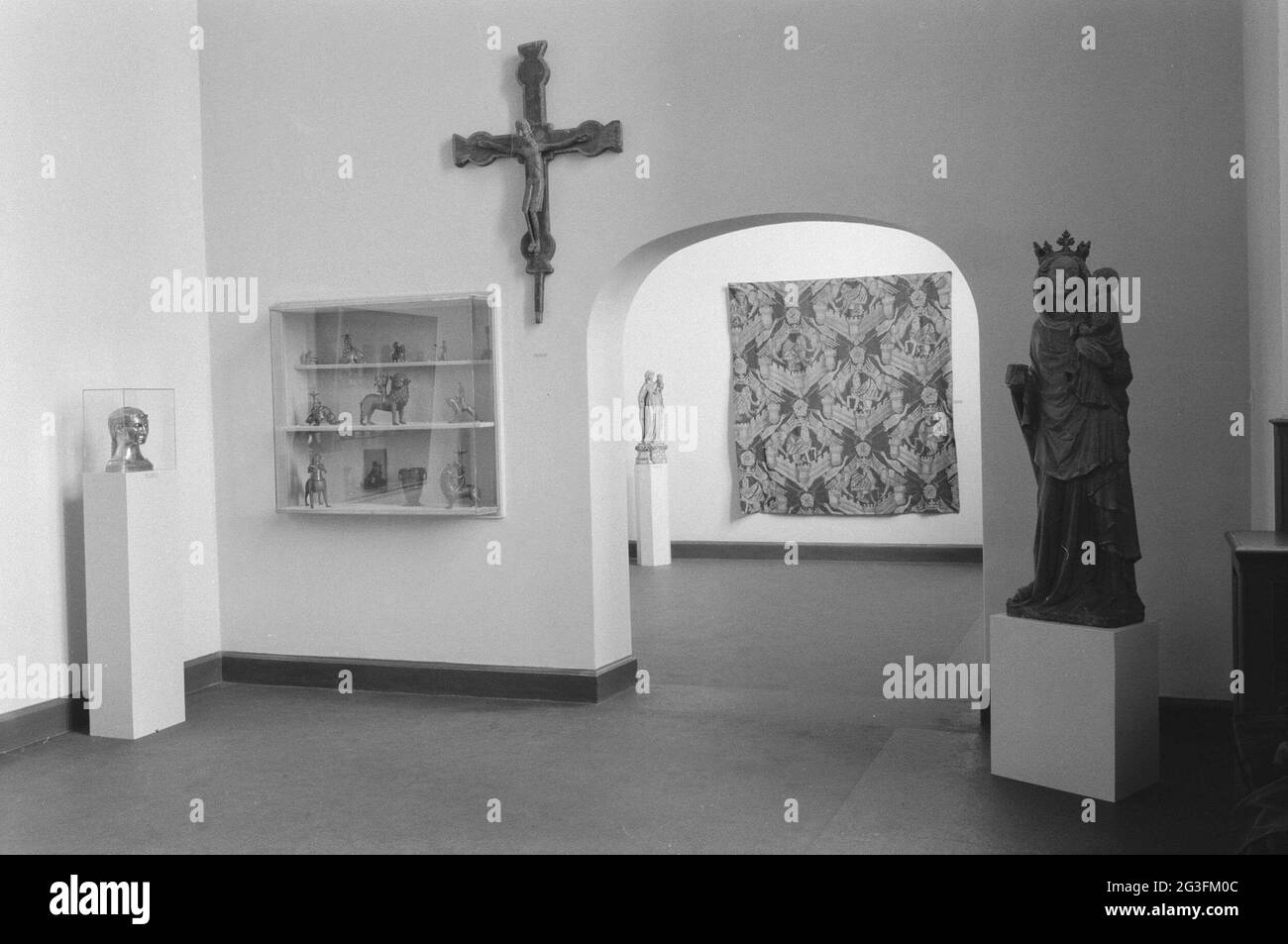 Room with image on base, crucifix, showcase and passage; Interiors West ...