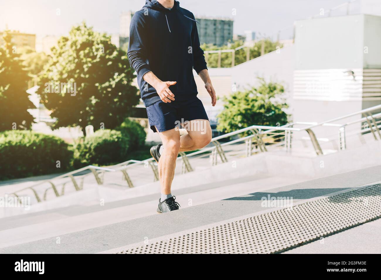 Young athlete man runner running up stairs on city stairs in summer on ...