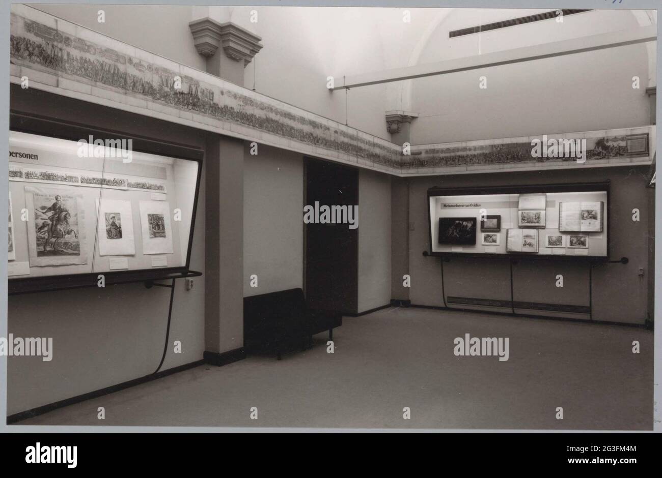 Room with various objects in showcases including prints over ...