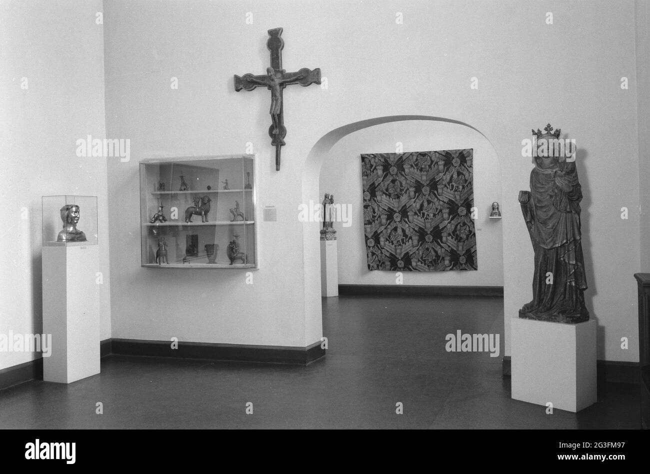 Hall with medieval crafts: images on pedestals, crucifix, display case ...