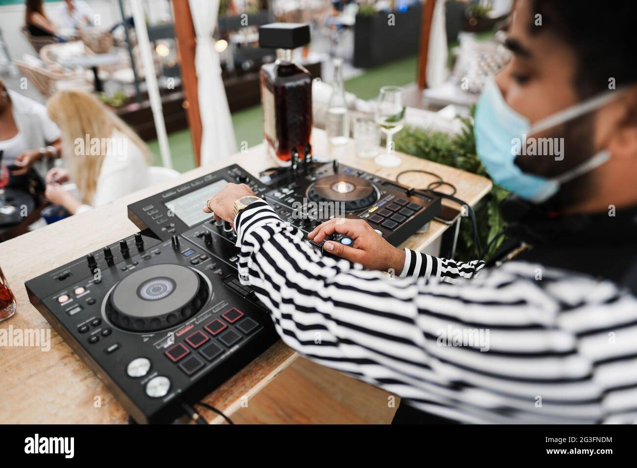 African dj playing music at cocktail bar outdoor while wearing face ...