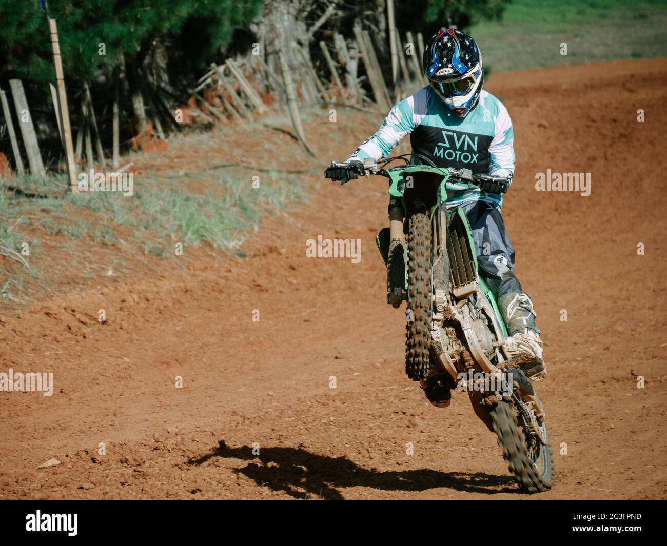 Motorbiker doing a wheelie on a dirt track Stock Photo - Alamy