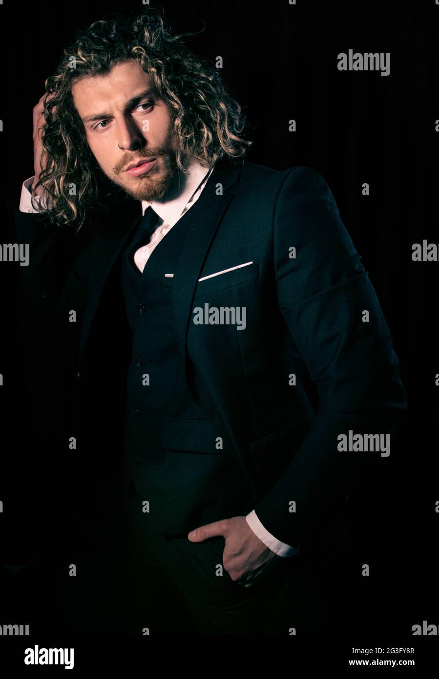 Low key lighting portrait of male ceo with long hair dressed in a suit ...