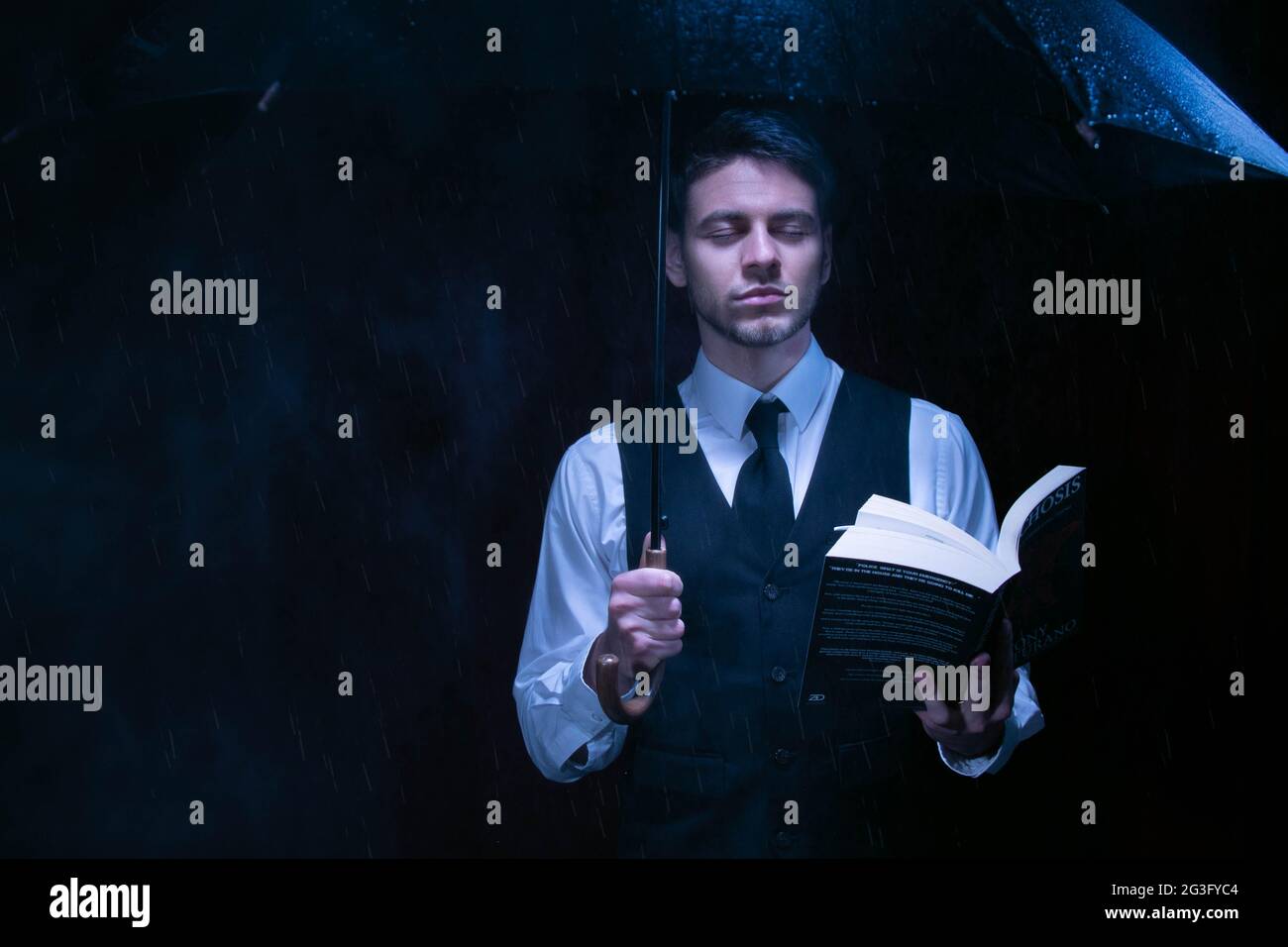 Man dressed in suit and tie holding unbrella and reading book Stock ...