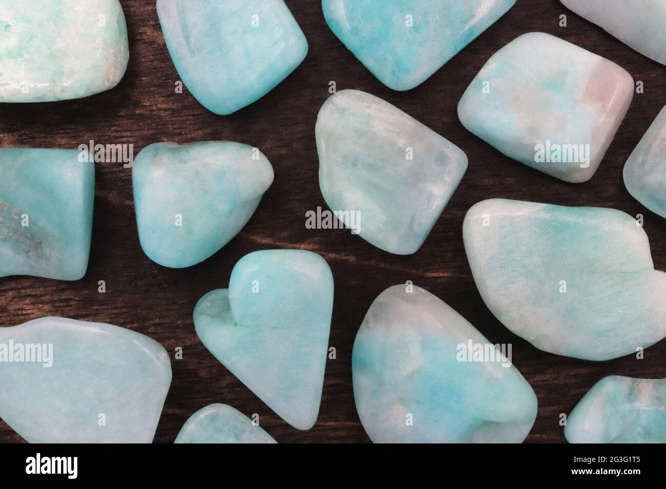 Amazonite rare jewel on black wood texture. Pile mineral pebbles ...