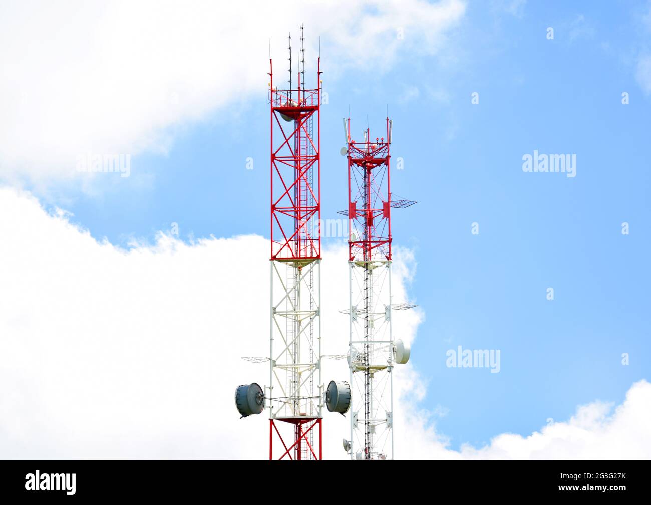 Two telecommunication towers with radio modules and antennas against a background of blue sky ...
