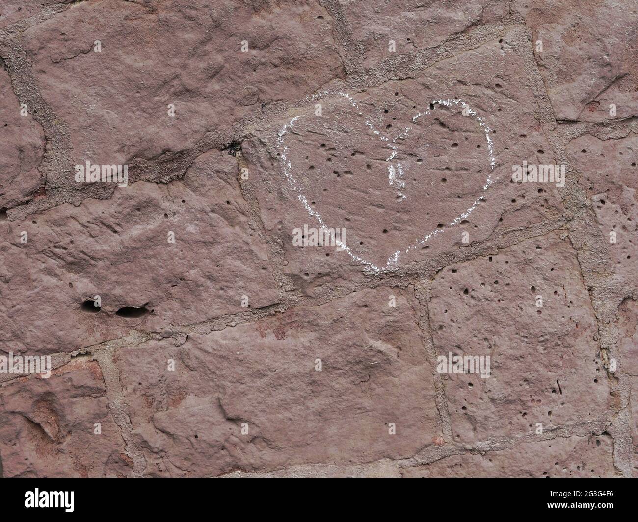 A white heart by an unknown artist on a red stone wall Stock Photo - Alamy