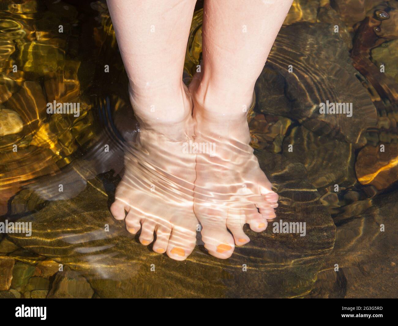 Dipping feet in water off a stone beach Stock Photo - Alamy