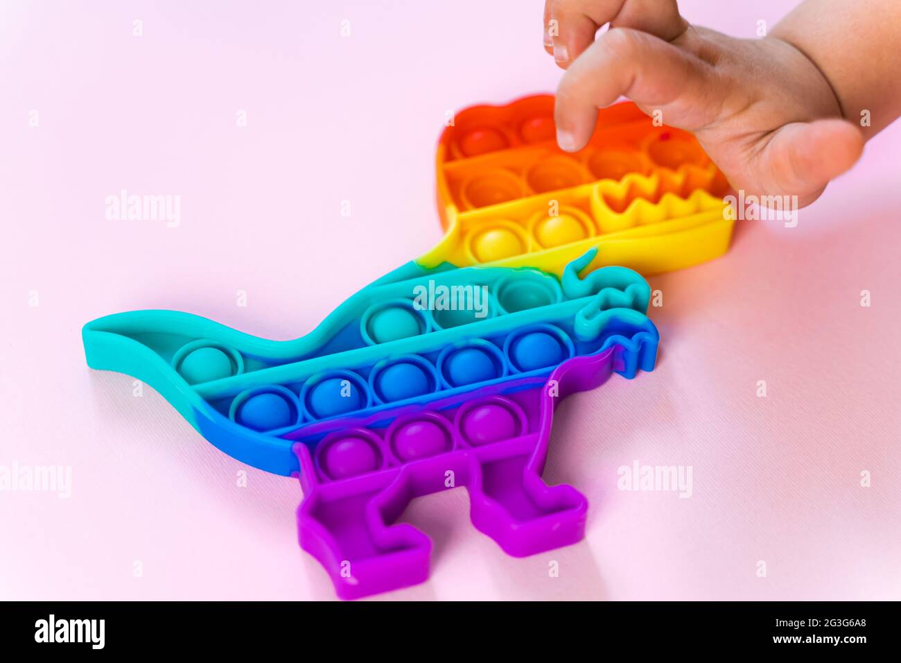 Popit rainbow toy in rainbow colours and dino shape. Trendy bubble pop ...