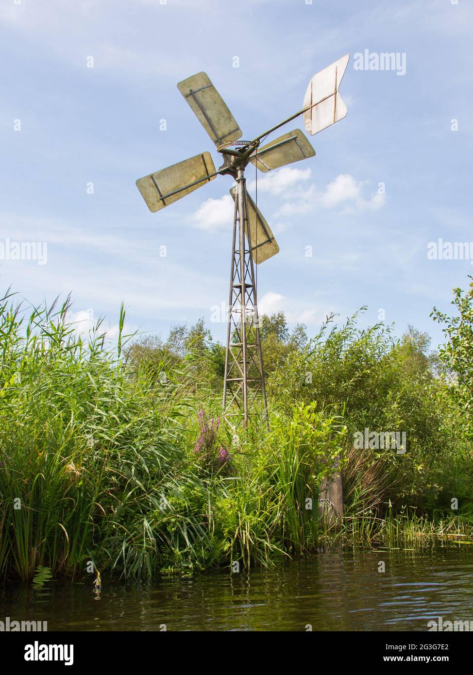 Small and rusted old metal windmill at the waterside Stock Photo - Alamy