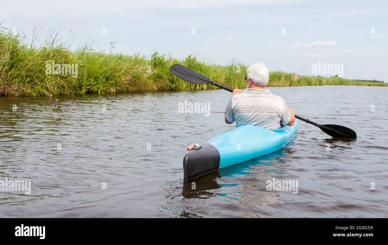 Man paddling in a blue kayak Stock Photo - Alamy