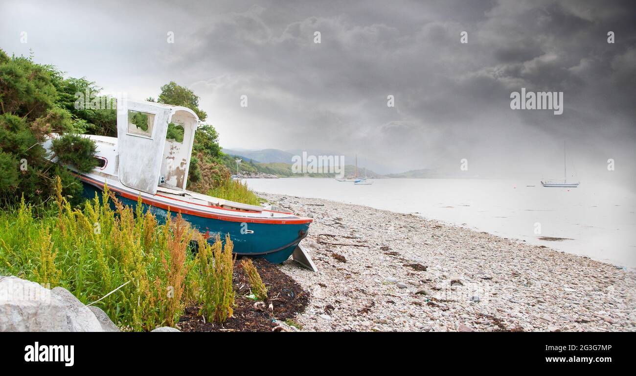 Small shipwreck at a loch with stone beach Stock Photo - Alamy