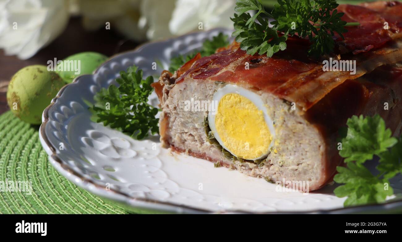 Easter background. Meatloaf wrapped in bacon with eggs Stock Photo - Alamy