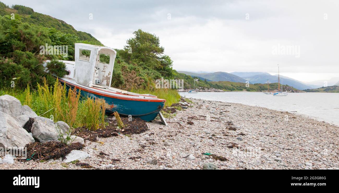 Small shipwreck at a loch with stone beach Stock Photo - Alamy