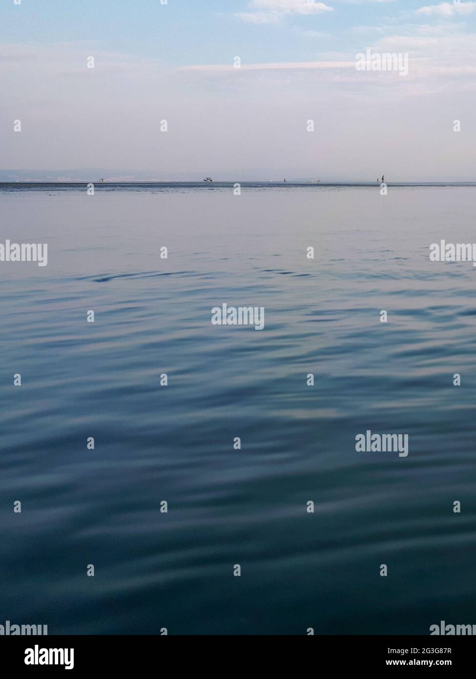 Tranquil water surface with soft ripples and distant horizon in Italy ...