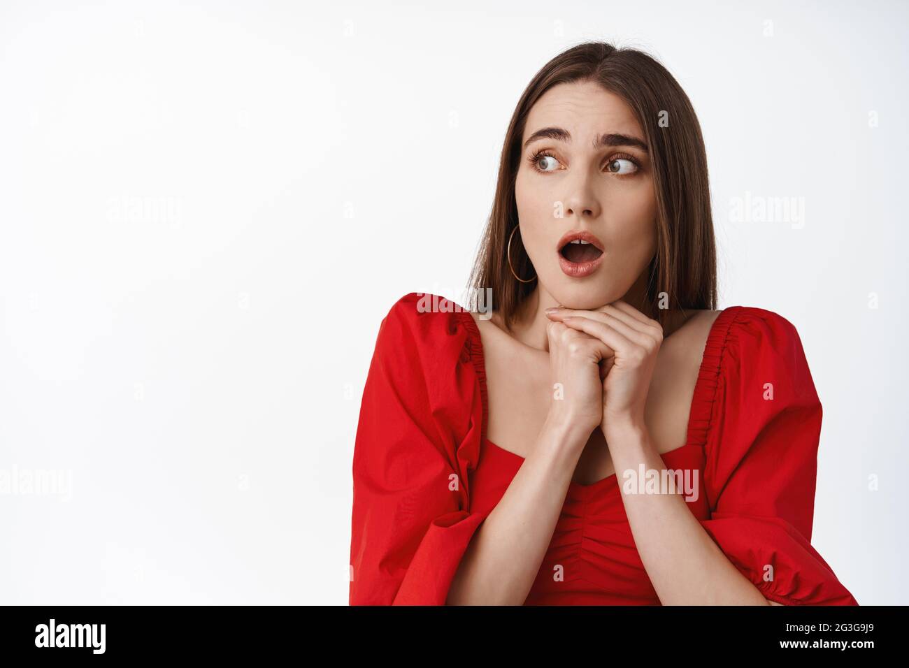 Image of shocked young woman looks startled to the left, staring at ...