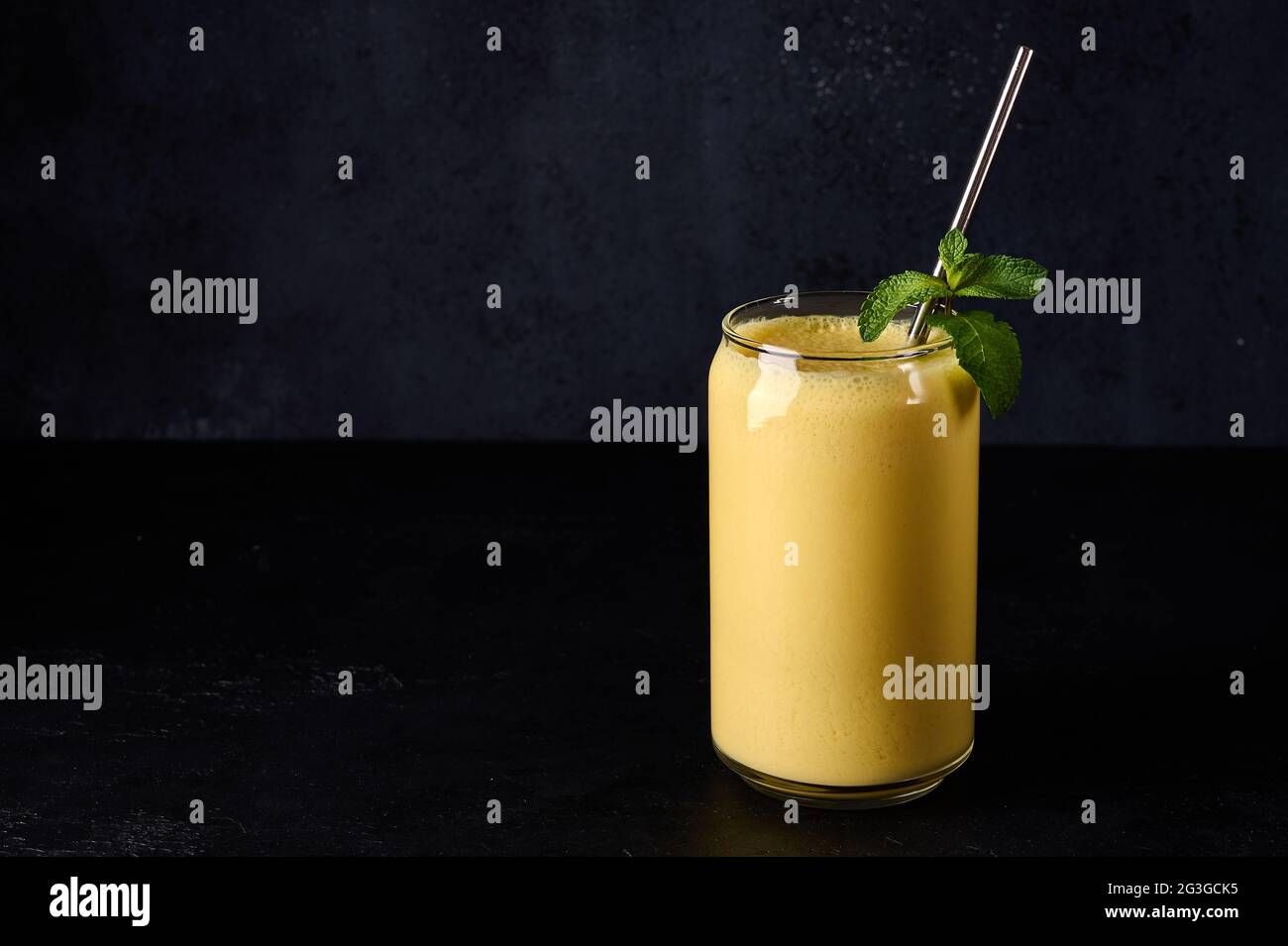 Mango lassi in glass with tube on dark background. Traditional Indian ...