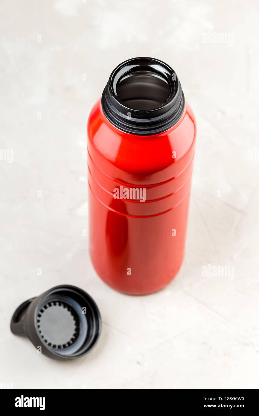 Red reusable steel thermo water bottle with open cap over grey ...