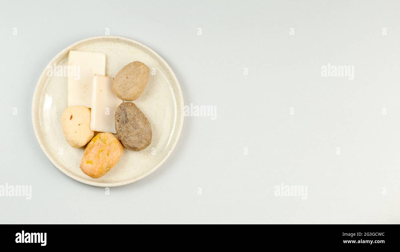 Handmade solid soap bars of different shape on white ceramic dish. Top ...