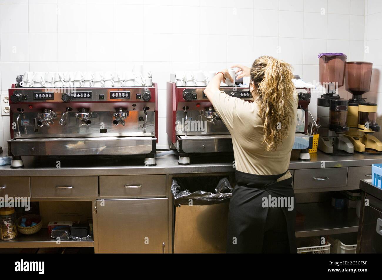 Back view of a female barista preparing a coffee with a coffee machine ...
