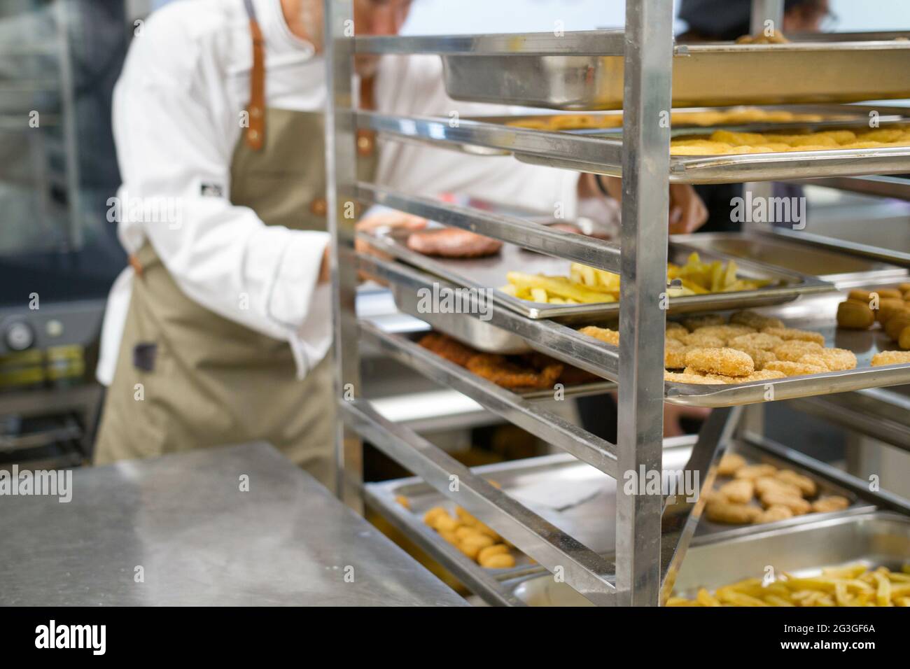 Cook taking a tray with prepared french fries in a restaurant kitchen ...