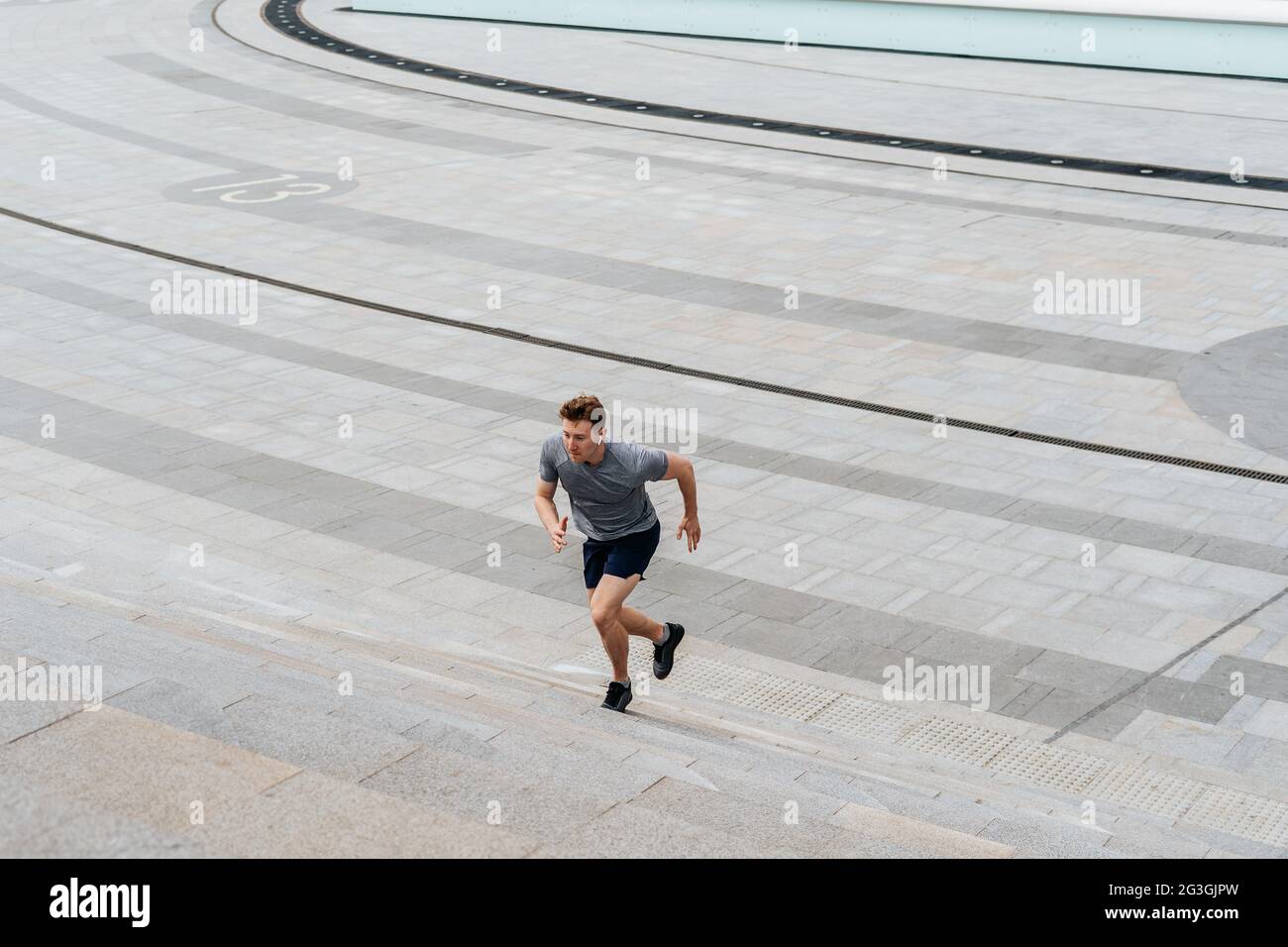Young athlete man runner running up stairs on city stairs in summer on ...
