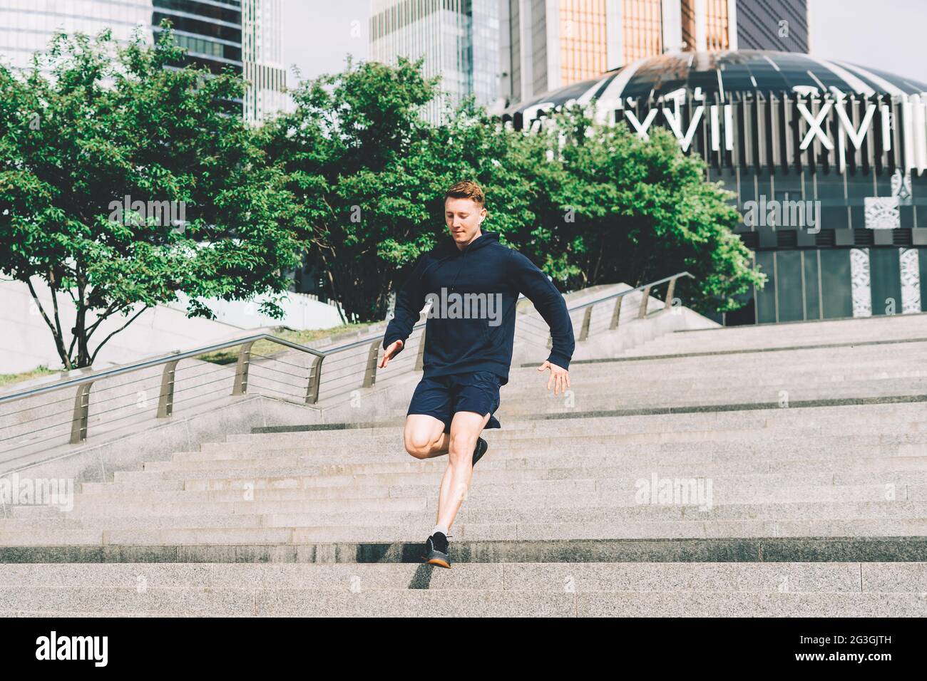 Young athlete man runner running up stairs on city stairs in summer on ...