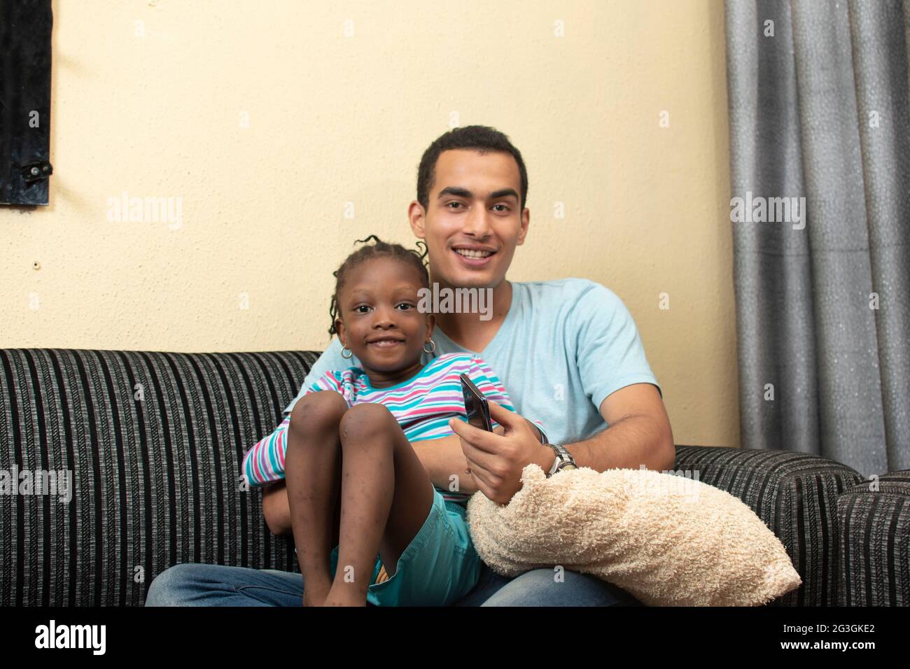 white father and daughter having a happy time together on the couch ...