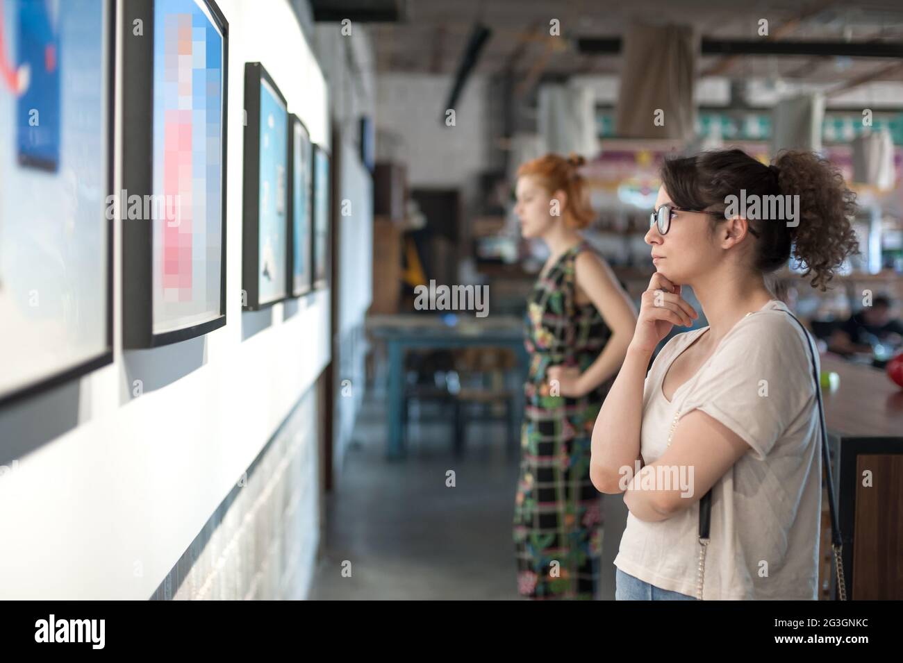 Young woman in modern art exhibition gallery hall contemplating artwork ...