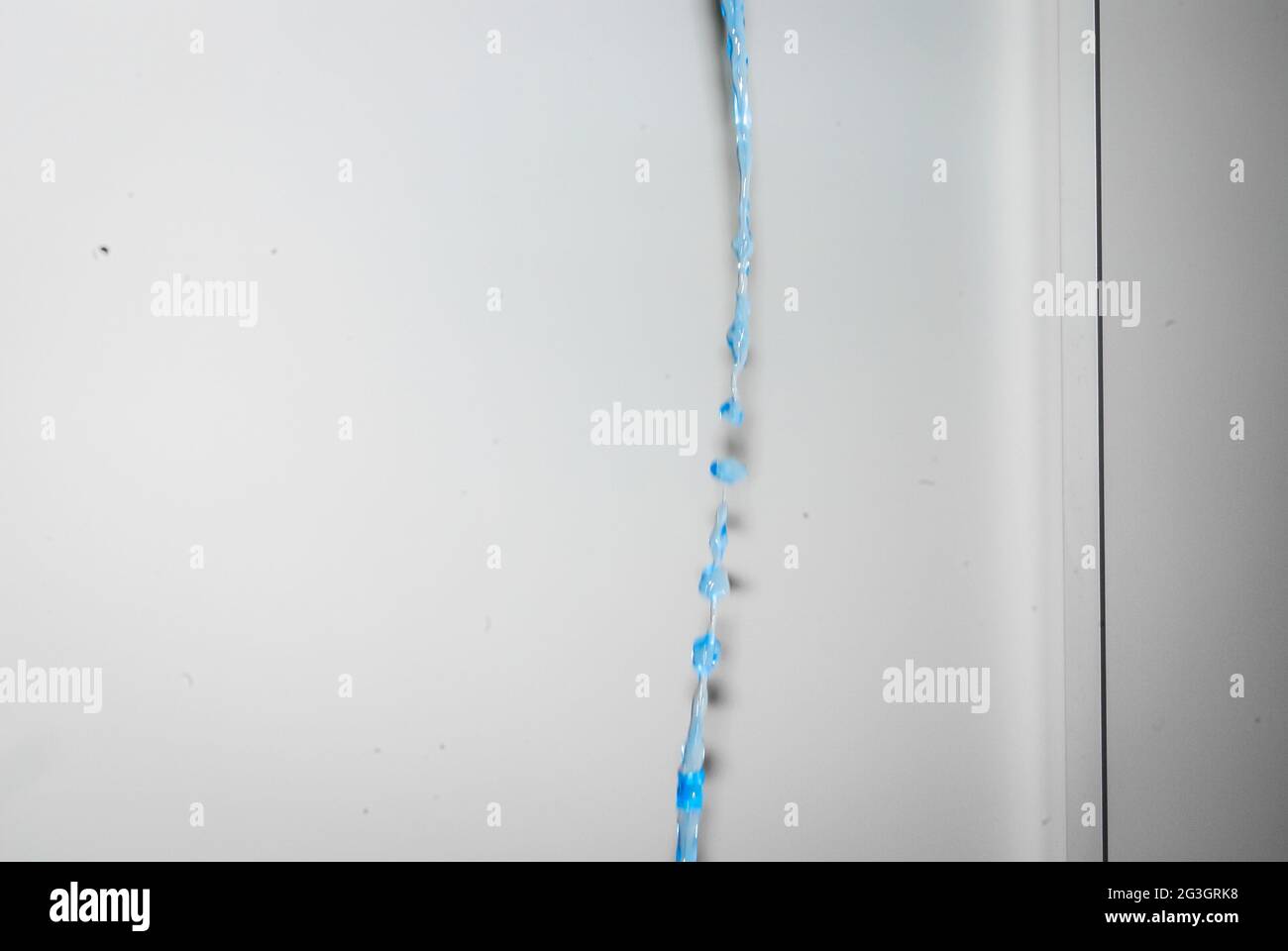 Blue colored water trickle white background Stock Photo - Alamy