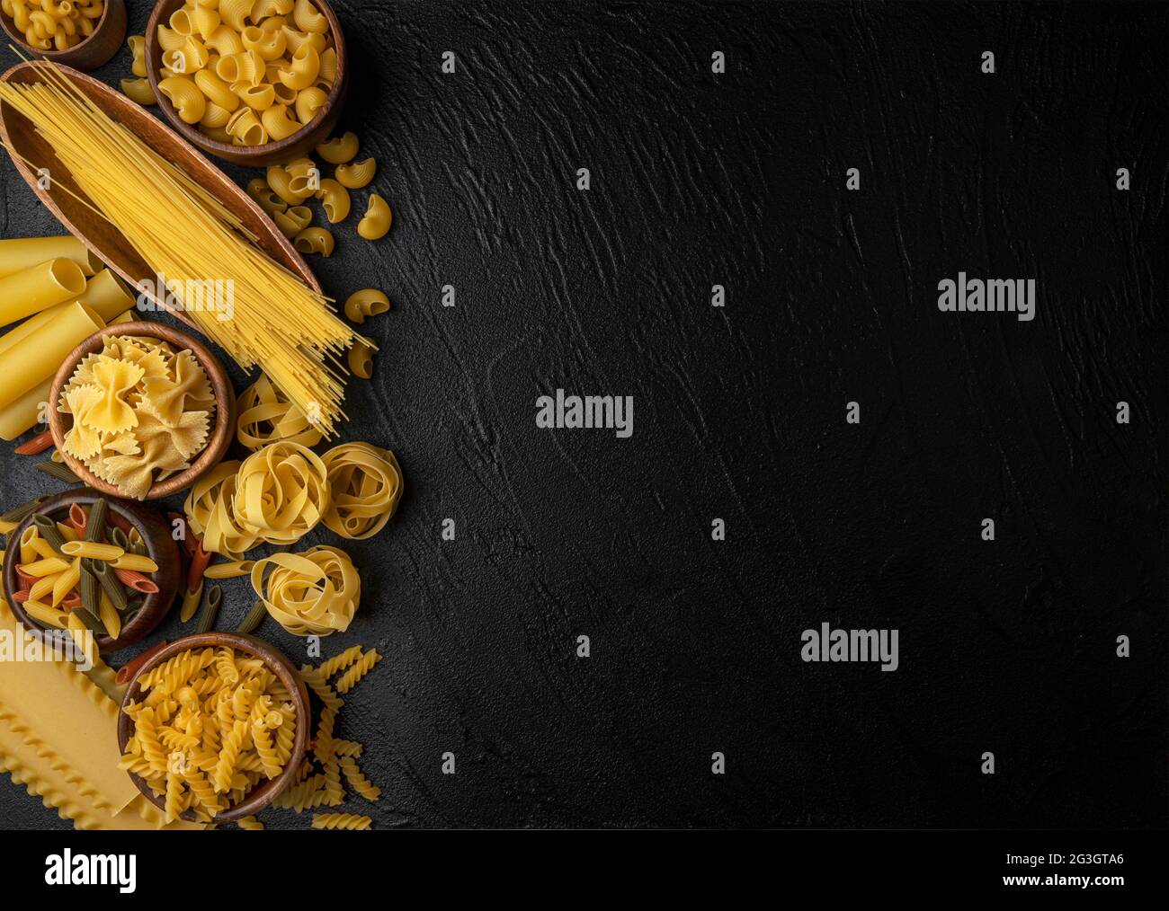Different pasta types on black background with copy space, top view ...