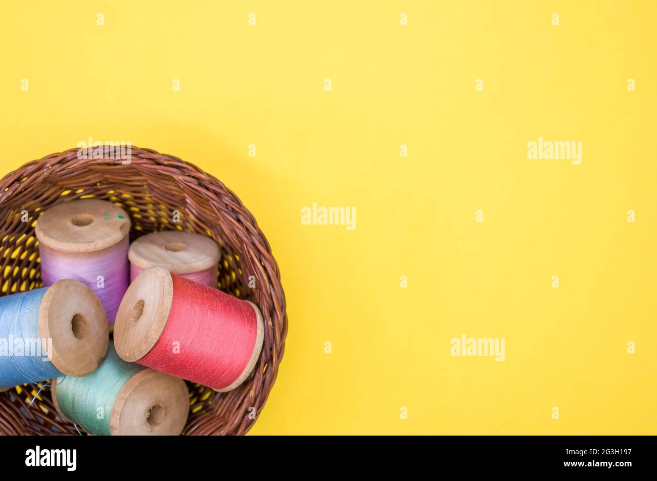 Basket of colorful sewing threads isolated on a yellow background with ...