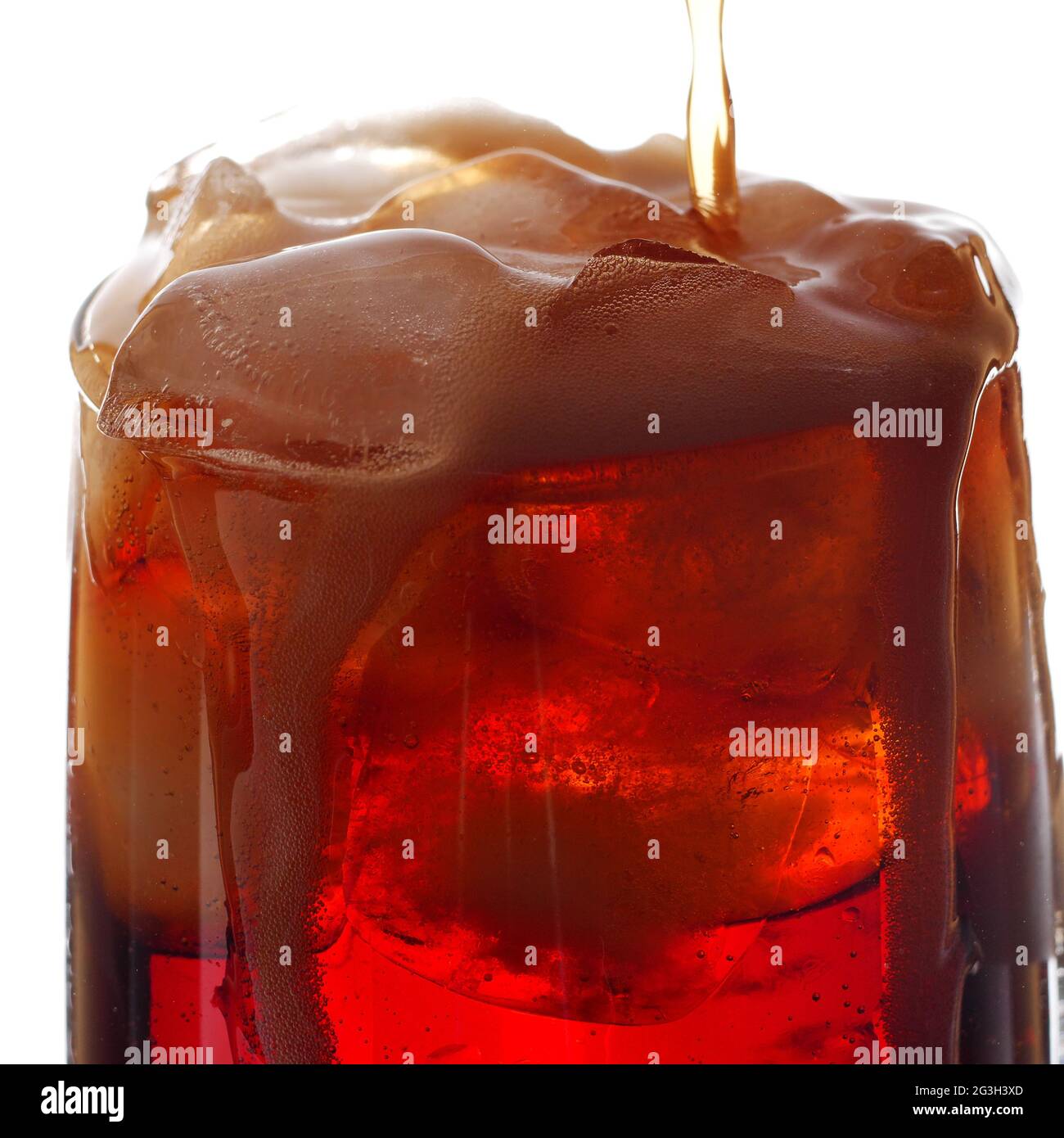 closeup on pouring cola into a glass with ice cubes, isolated on white ...
