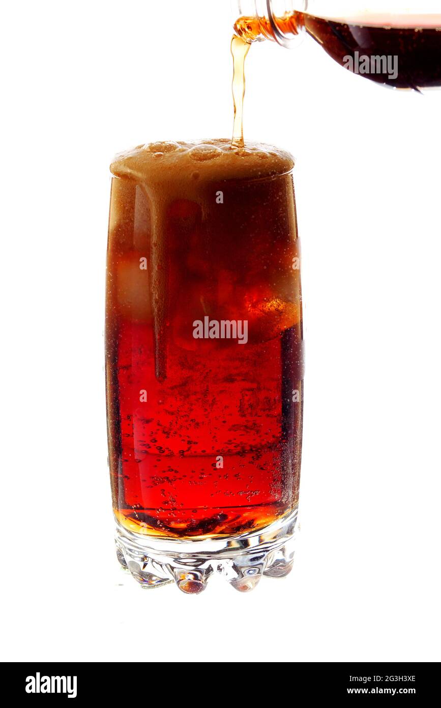 pouring cola into a glass with ice cubes, isolated on white background ...