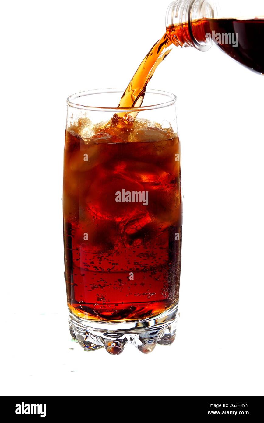 pouring cola into a glass with ice cubes, isolated on white background ...