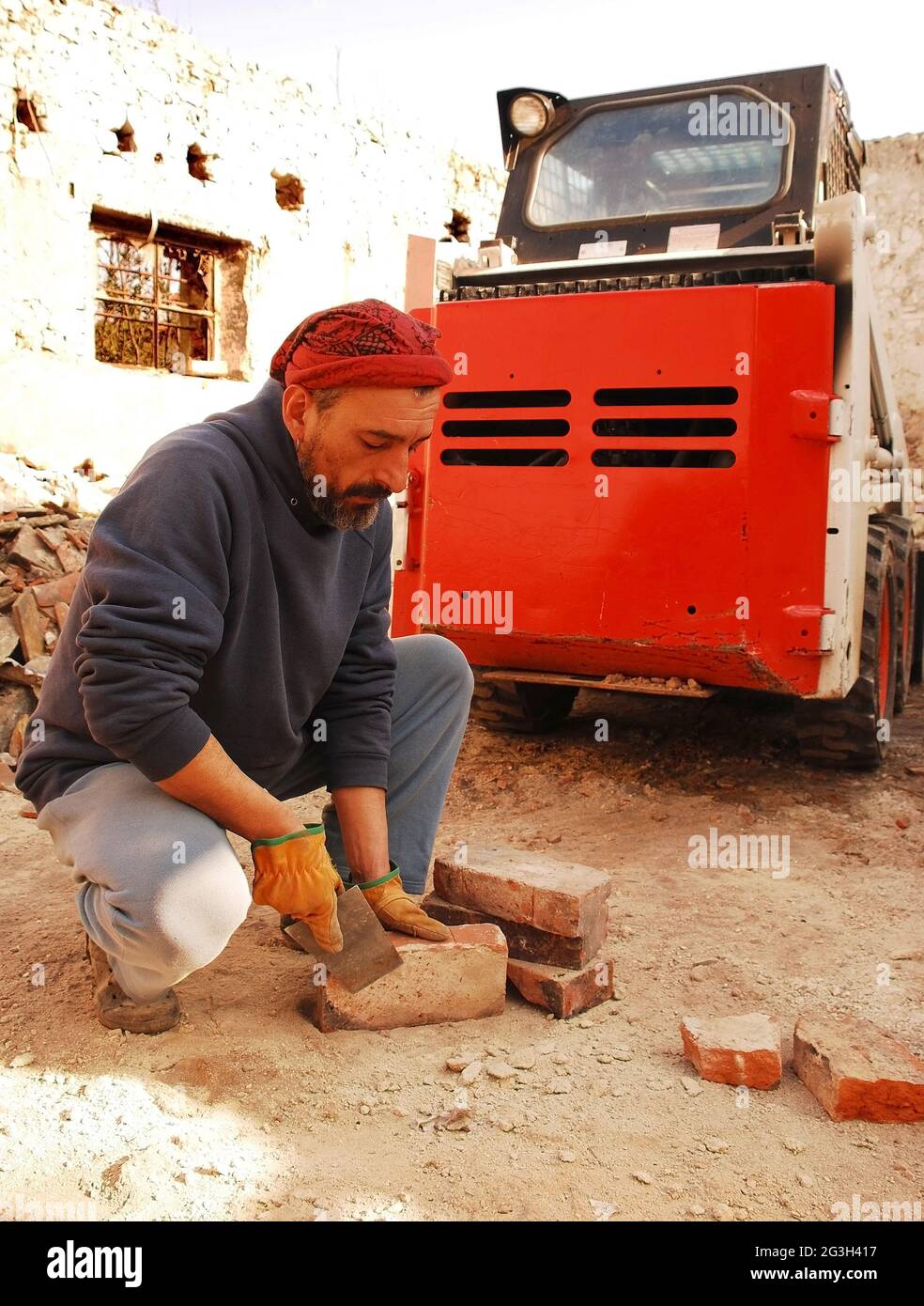 A man scrapes excess cement from antique bricks being salvaged for ...