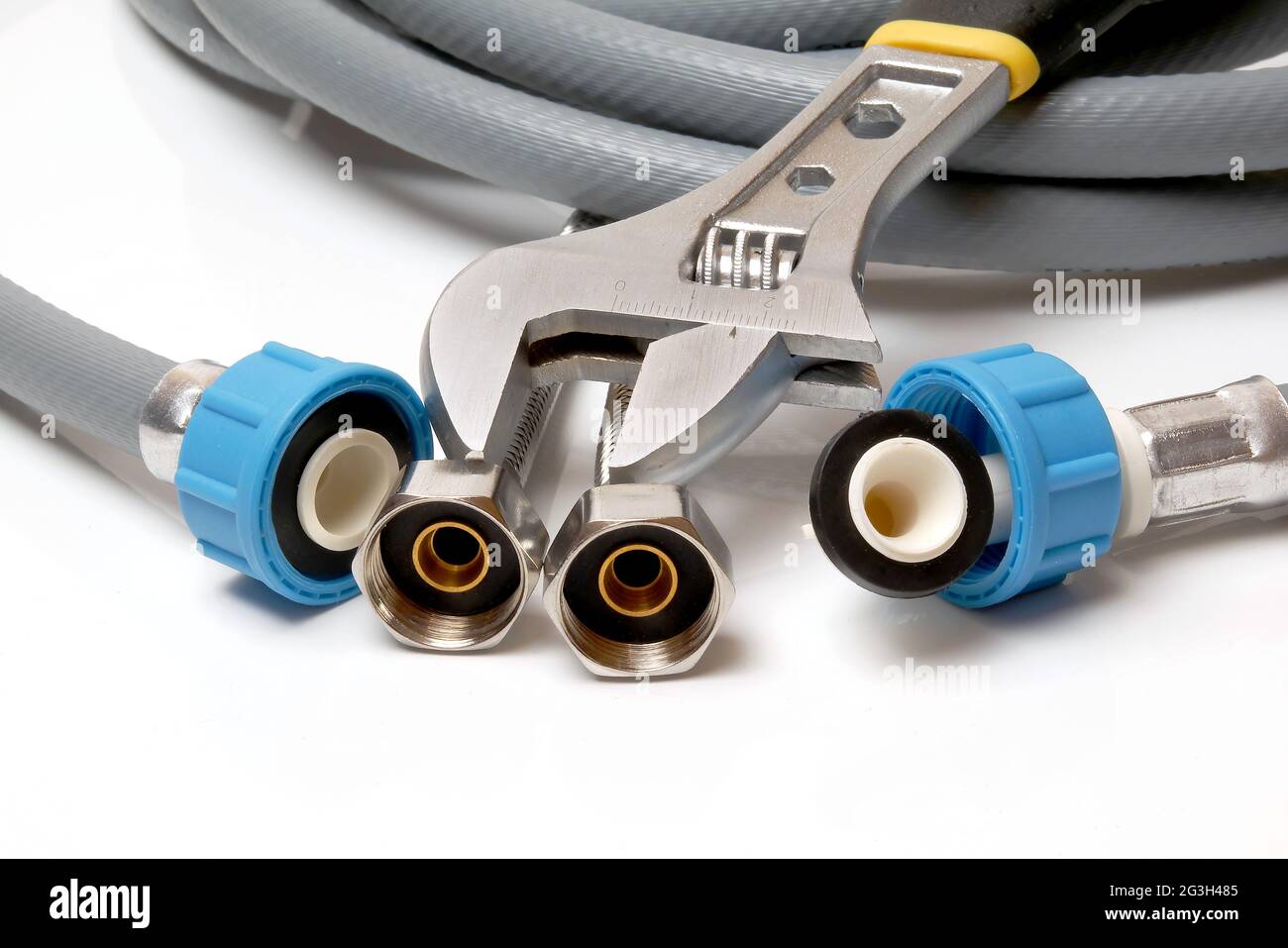closeup on flexible water supply tubes and adjustable wrench on white ...