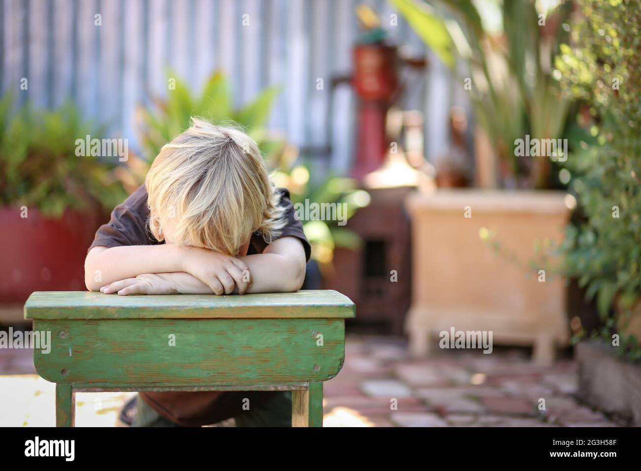 Adorable blonde Australian kid sitting and leaning on a small school ...
