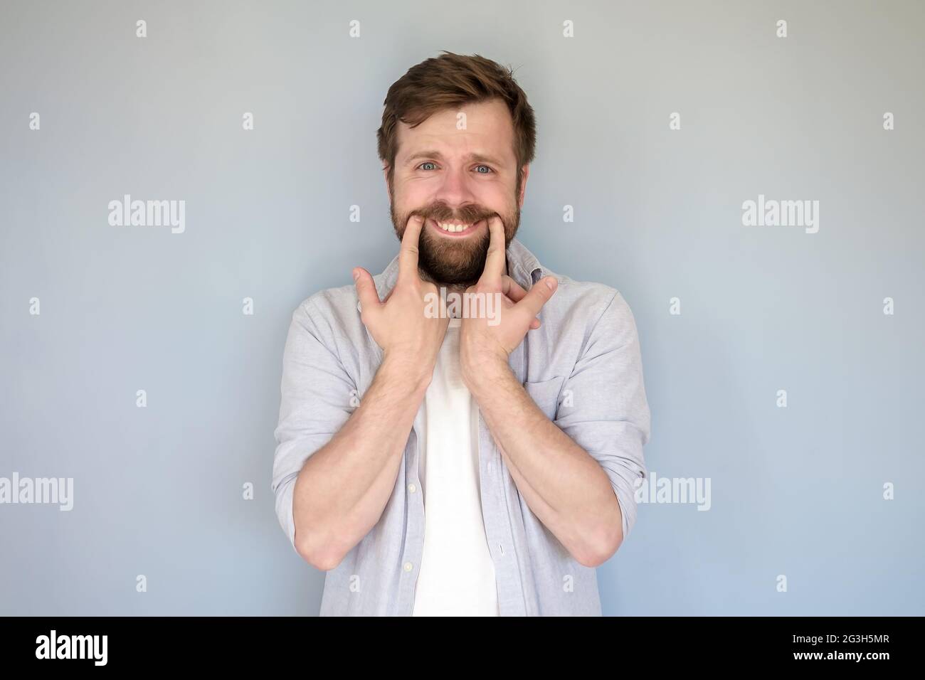 Upset bearded man with sad, tear-stained eyes makes himself an ...