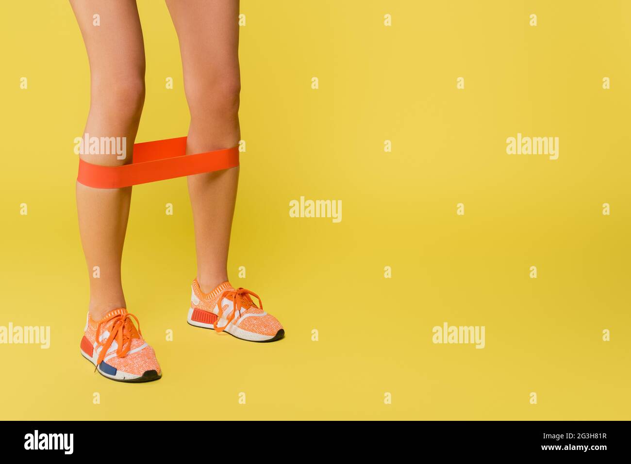 cropped view of sportswoman training with resistance band on legs on ...