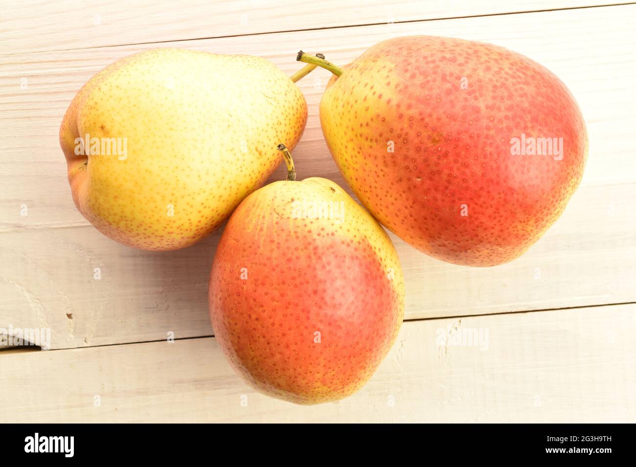 Three organic yellow-red pears, close-up, on a wood table, top view ...
