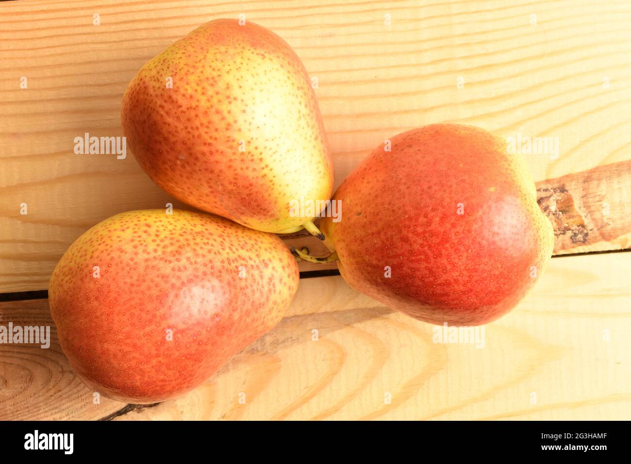 Three organic yellow-red pears, close-up, on a wood table, top view ...