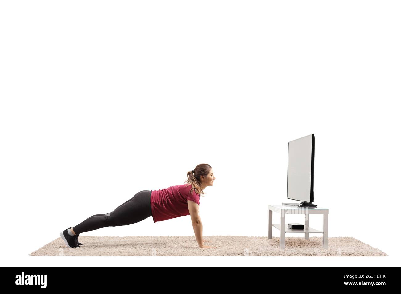 Young woman doing plank exercise in front of a tv isolated on white ...