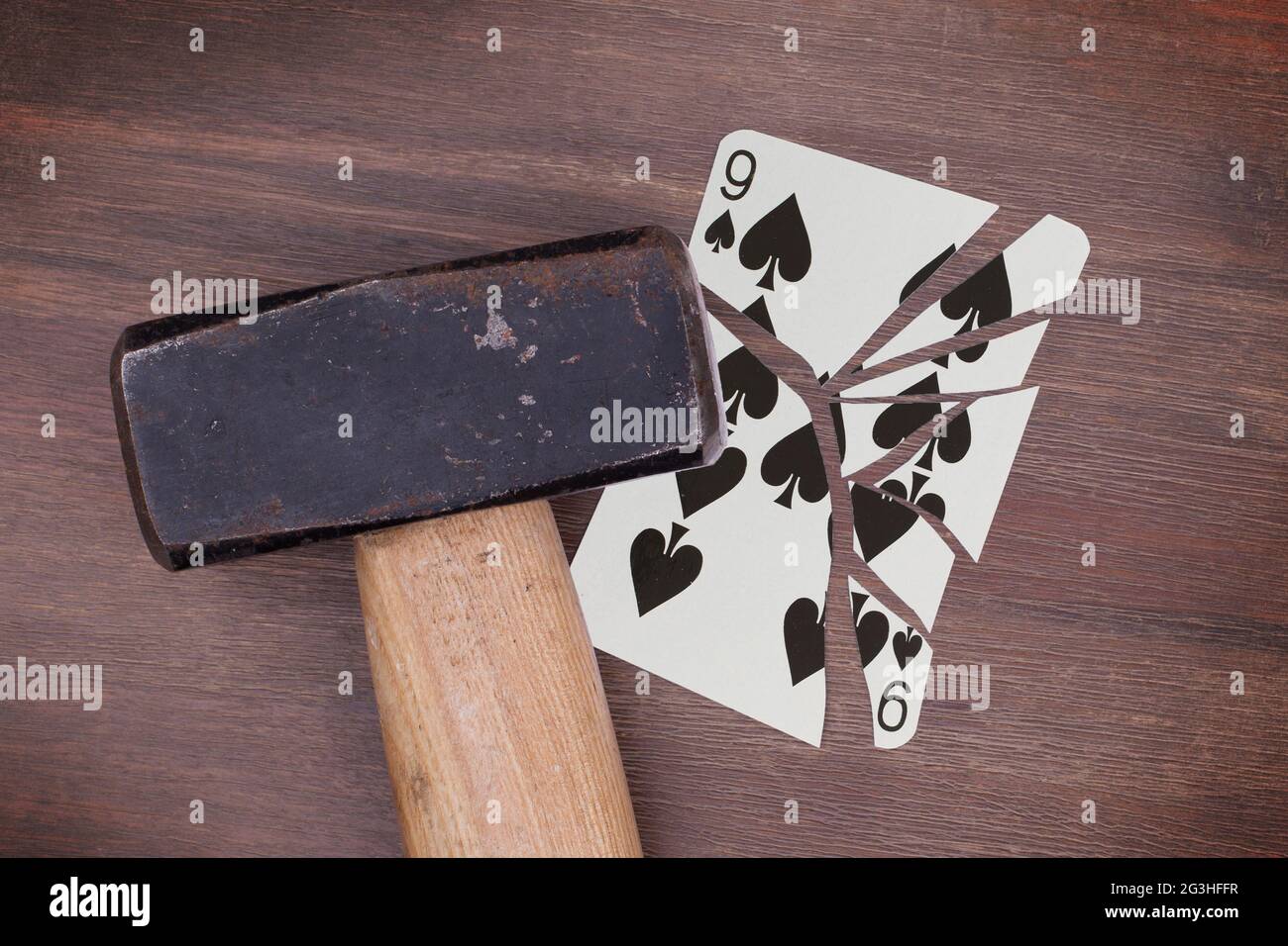 Hammer with a broken card, nine of spades Stock Photo - Alamy