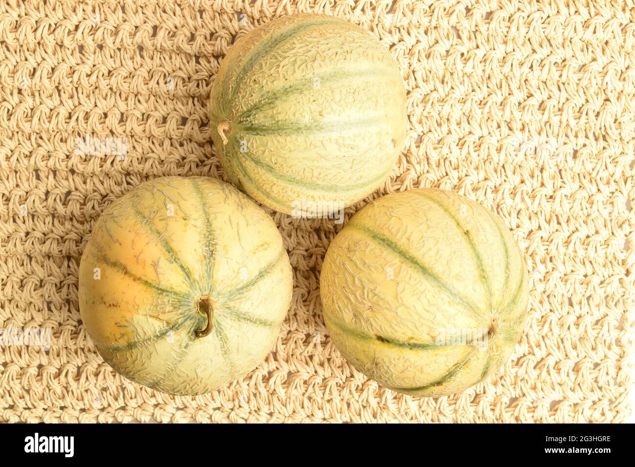 Three fragrant juicy, organic melons, close-up, on a straw mat, top ...