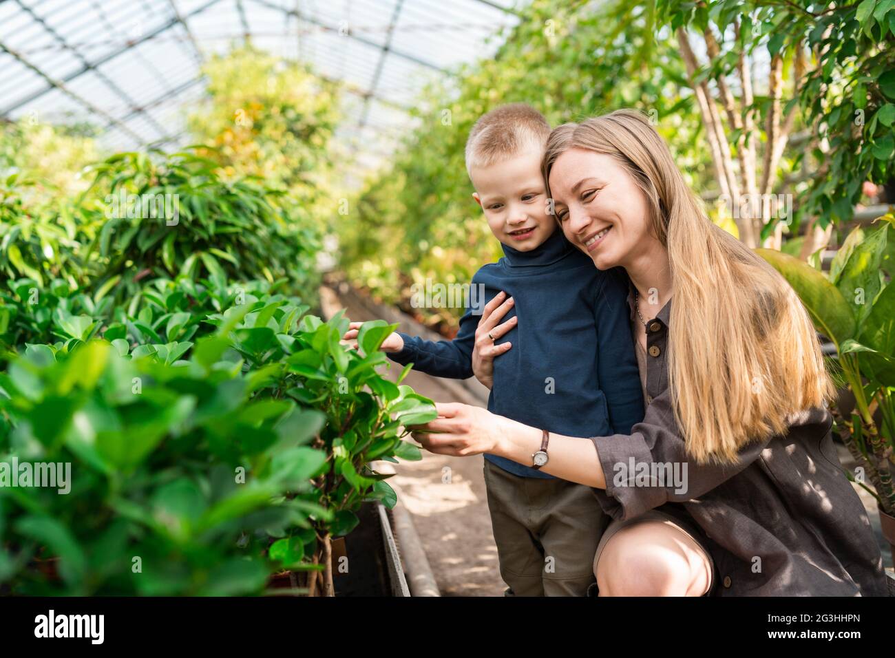 Mom hugs her son in a greenhouse with plants Stock Photo - Alamy