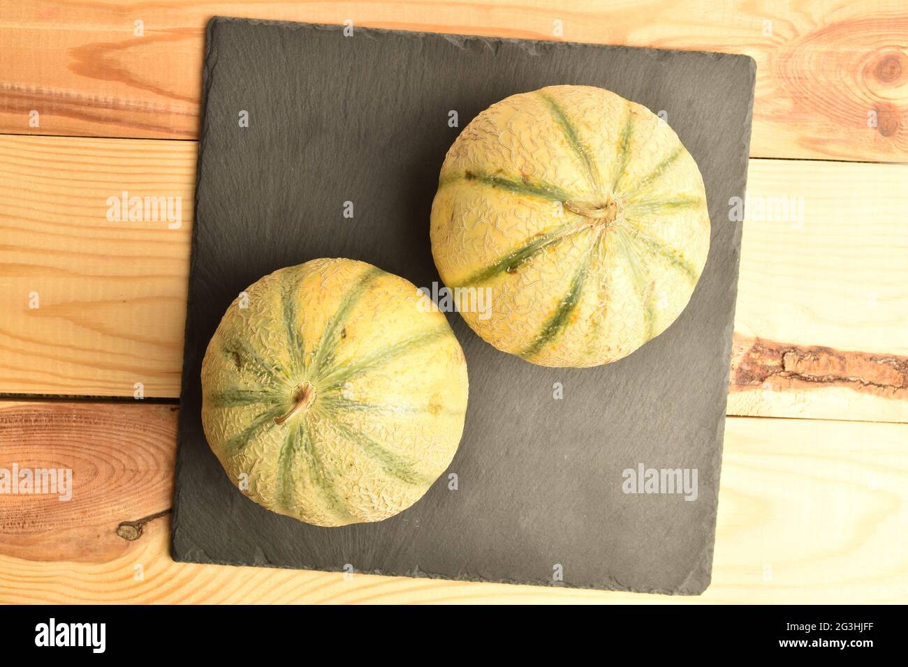 Two fragrant organic melons on a serving slate board, close-up, on a ...