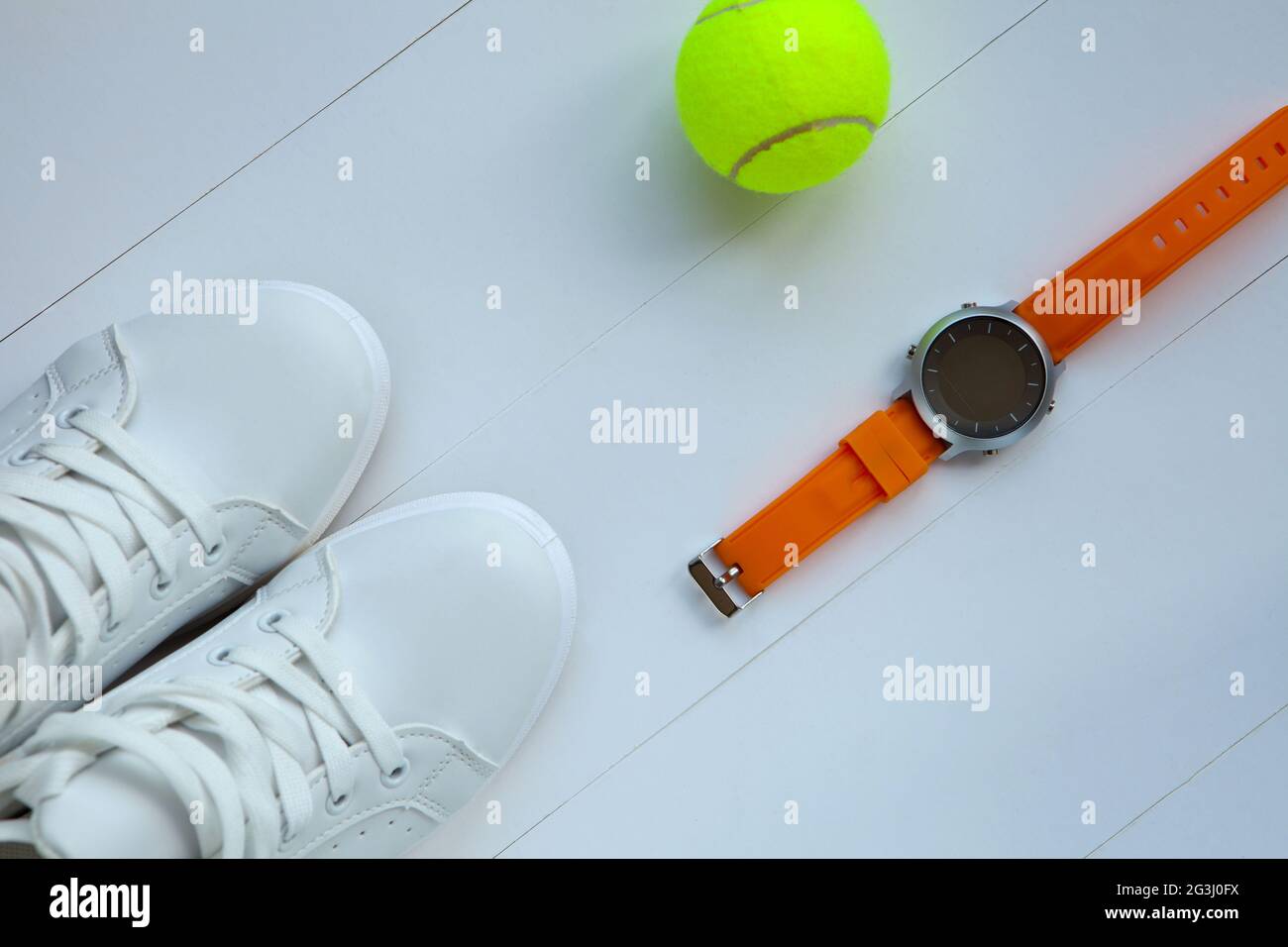 white tennis shoes, tennis ball and orange sport watch. sportequipment ...